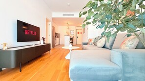 Uma sala de estar moderna com televisão de tela plana, um sofá, uma mesa de centro e uma planta.
