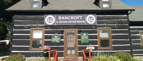 Uma cabana de toras com uma placa para o Bancroft N. Hastings Heritage Museum.