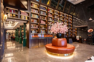 Uma biblioteca com estantes, lareira e um espaço de estar com um vaso de flores.