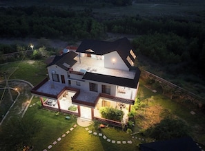 Uma casa de dois andares com varanda coberta e um jardim visível.