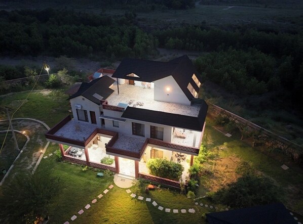 Uma casa de dois andares com varanda coberta e um jardim visível.