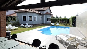 Piscina com espreguiçadeiras e área de terraço.