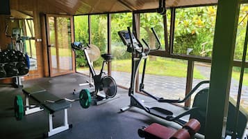 Uma academia com equipamentos de ginástica, um banco e uma estante de pesos.