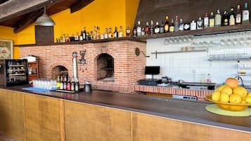 Uma área de bar com forno de tijolos, diversos tipos de bebidas e uma tigela de limões.