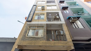 Um edifício de vários andares com varandas, aparelhos de ar condicionado e uma placa com o nome Satguru Transport.