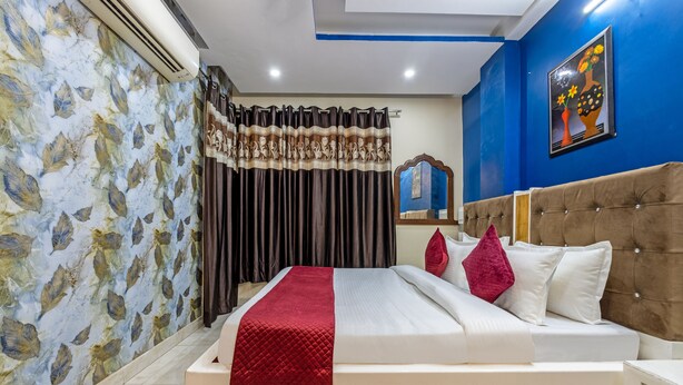 Quarto de hotel com cama, cortinas, um quadro e parede azul.