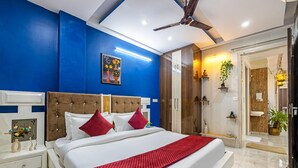 Quarto com uma cama grande, um ventilador de teto e uma parede azul.