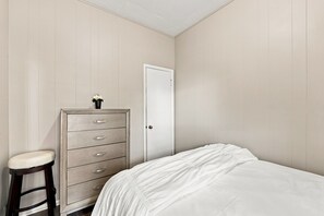 Quarto com uma cama, cômoda e porta.