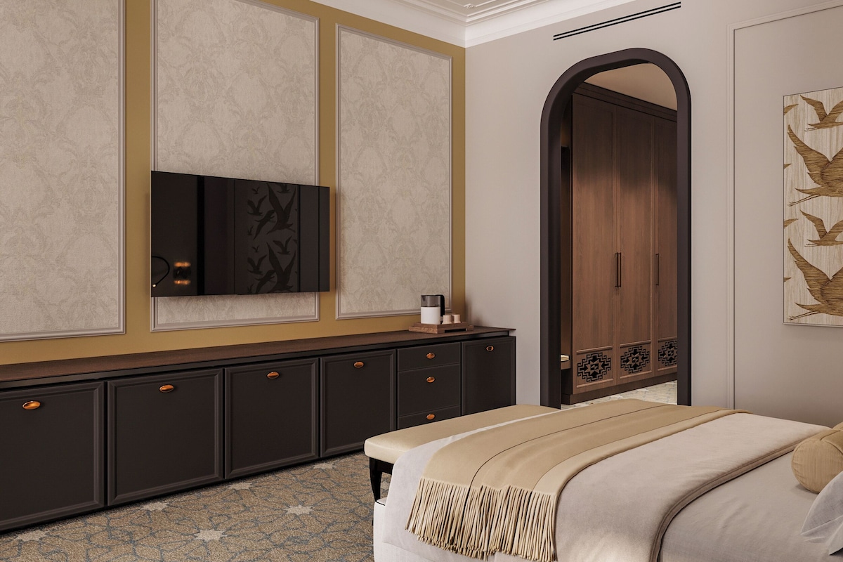 Quarto com cama, televisão na parede, guarda-roupa e porta em arco.