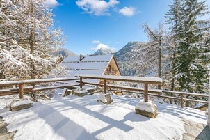 Um deck de madeira coberto de neve com vista para uma montanha e um chalé.
