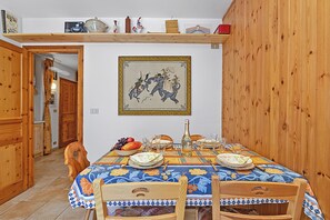 Uma sala de jantar com uma mesa posta para quatro pessoas, rodeada por cadeiras de madeira.