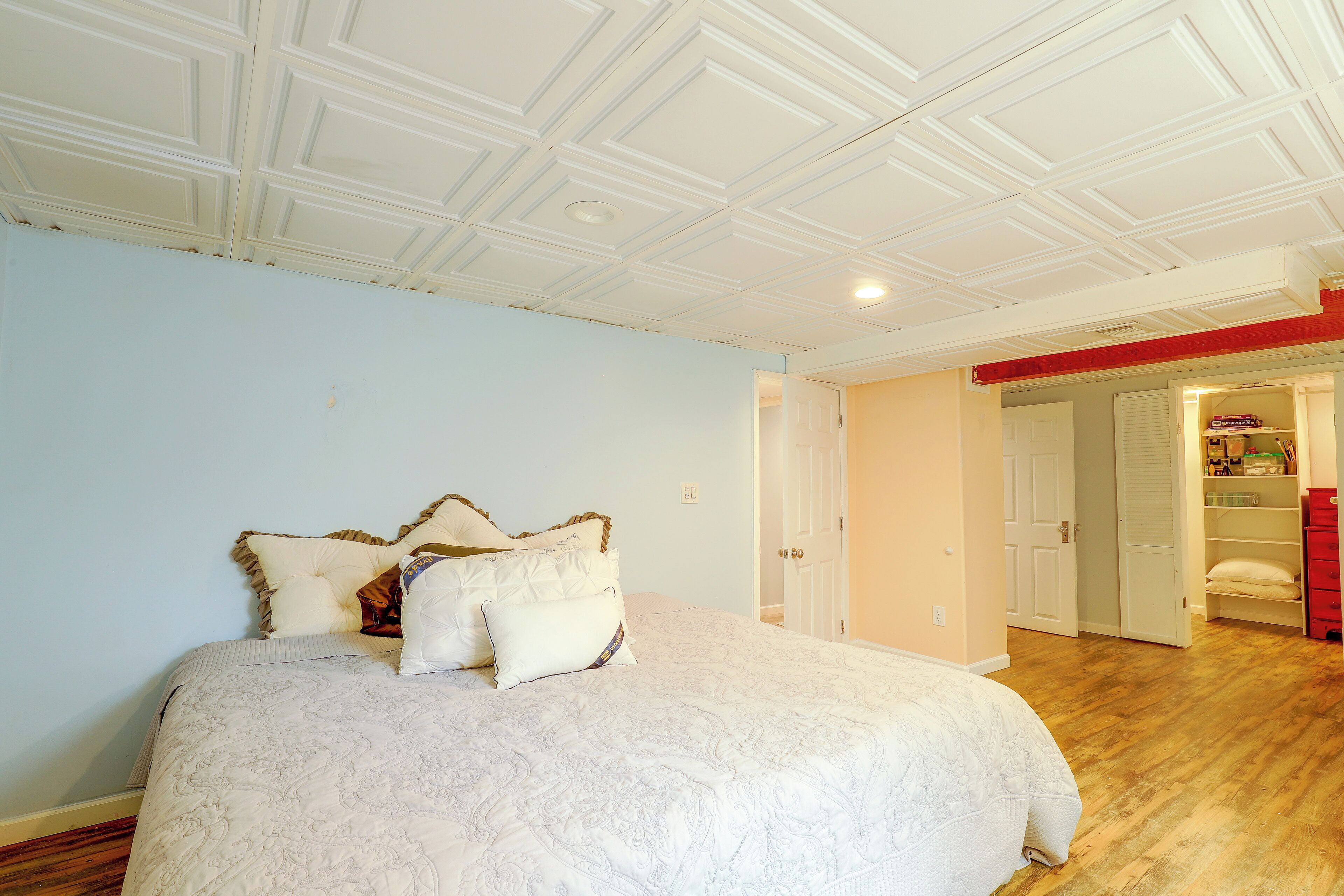 Quarto com cama grande, um guarda-roupa e porta que dá para outro cômodo.