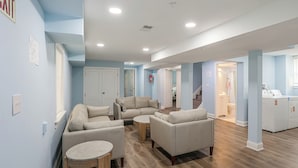 Uma sala de estar ampla com sofás, uma mesa de centro e uma lavanderia com máquina de lavar.