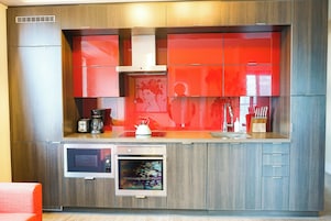Cozinha moderna com eletrodomésticos embutidos, micro-ondas, forno e cafeteira.