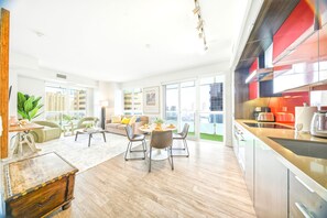 Uma sala espaçosa com mesa de jantar, cadeiras, sofá e cozinha equipada com eletrodomésticos modernos.