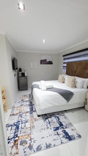 Quarto com cama, mesa de cabeceira e televisão.