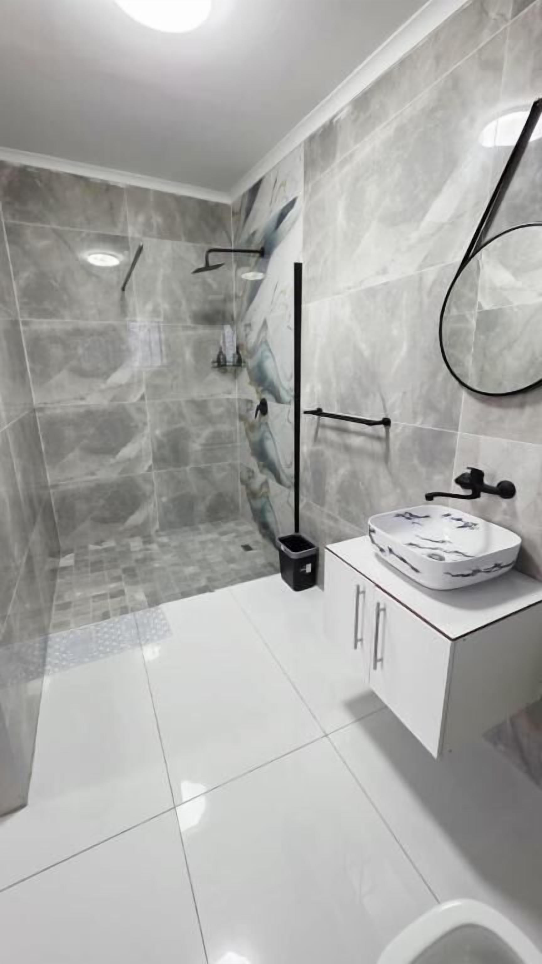 Uma casa de banho moderna com chuveiro, sanita e lavatório.