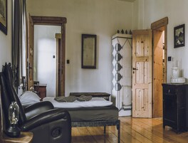 Um quarto com cama, guarda-roupa de madeira, penteadeira e espelho.