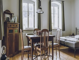 Um quarto com uma mesa de madeira, quatro cadeiras, um armário e uma cama.