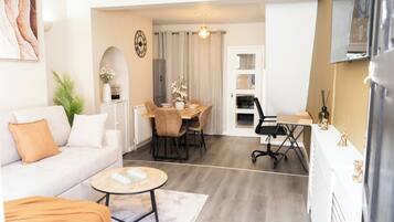 Uma sala de estar moderna com um sofá, mesa de centro e um espaço de refeições com cadeiras e mesa.