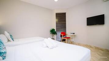 Quarto de hotel com duas camas, televisão, uma mesa pequena e uma cadeira vermelha.
