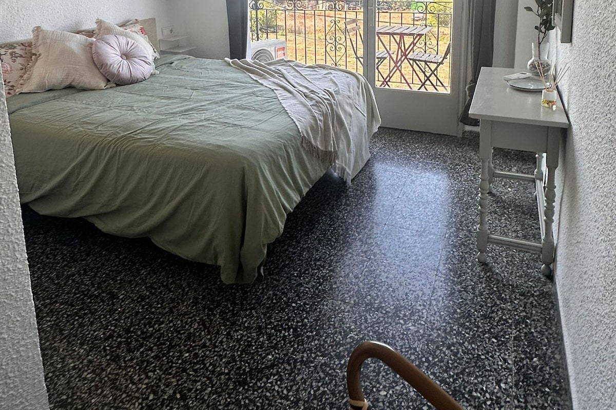 Quarto de hotel com cama, escrivaninha, cadeira, varanda e ar condicionado.