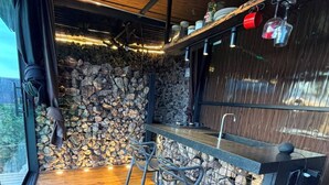 Uma cozinha moderna com parede de pedra, piso de madeira e banquetas de bar.