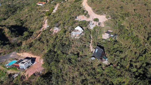 Vista aérea de uma propriedade com piscina, um pequeno edifício e uma grande instalação de painéis solares.