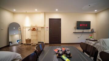 Quarto de hotel com mesa de jantar posta para dois, televisão fixada na parede e porta com moldura de madeira.