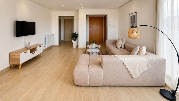 Uma sala de estar moderna com sofá, televisão e abajur.