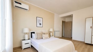 Um quarto com cama, mesas de cabeceira, radiador e ar condicionado.