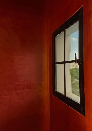 Janela com moldura preta e vista para o verde lá fora.