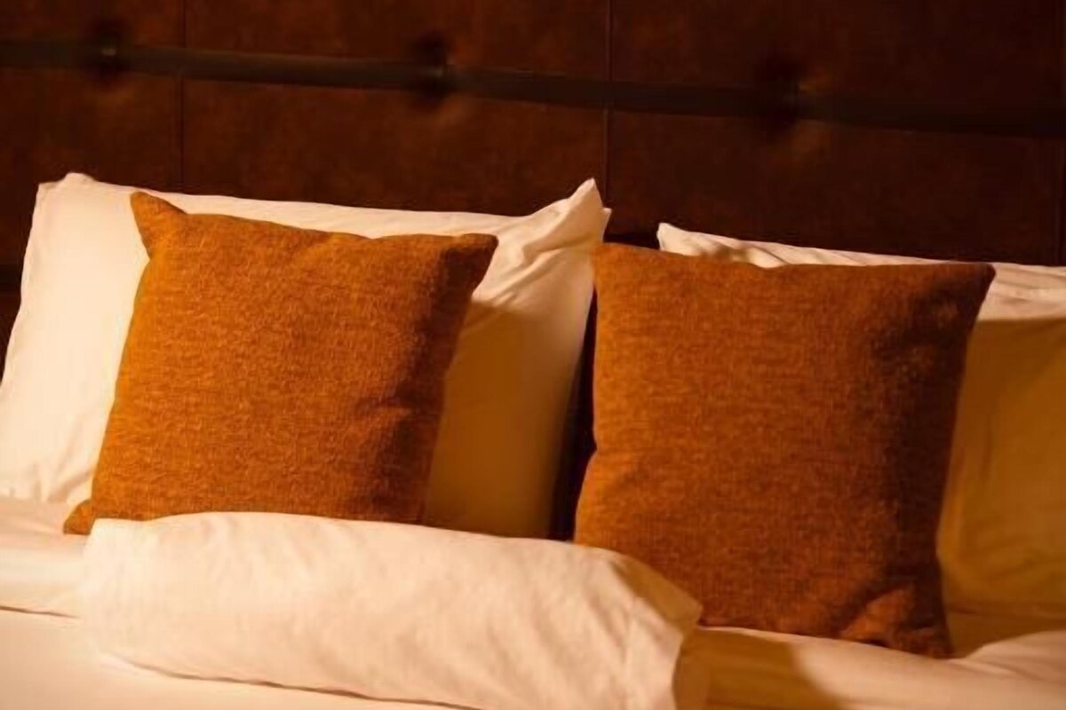 Uma cama com cabeceira, almofadas e um cobertor.