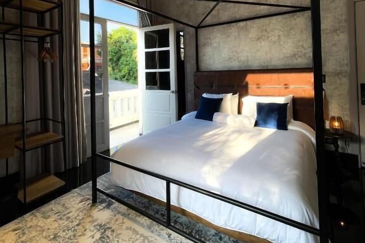 Quarto moderno com cama de dossel, prateleira embutida e vista para o exterior.