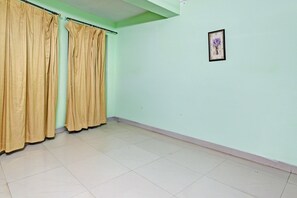 Quarto com piso de azulejos, paredes verde-claras e um quadro na parede.