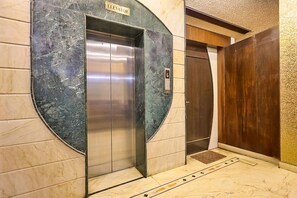 Um elevador com parede de mármore e porta de madeira.