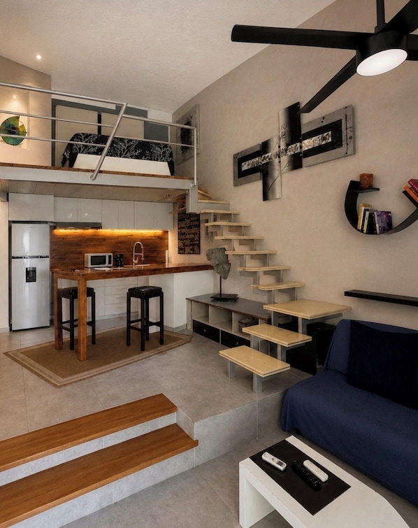 Um apartamento moderno com cozinha, área de refeições e escada que leva a um mezanino.