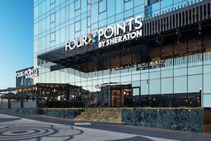 Um edifício moderno com fachada de vidro e placa indicando 'Four Points by Sheraton'.