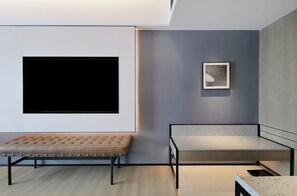 Uma sala de estar moderna com uma grande televisão de tela plana fixada na parede, um banco e uma pequena mesa.