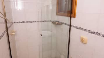 Uma casa de banho com chuveiro em cabine de vidro, sanita e lavatório com toalha.