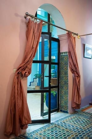 Um quarto com uma grande porta em arco, um chão estampado e vista para uma escadaria.