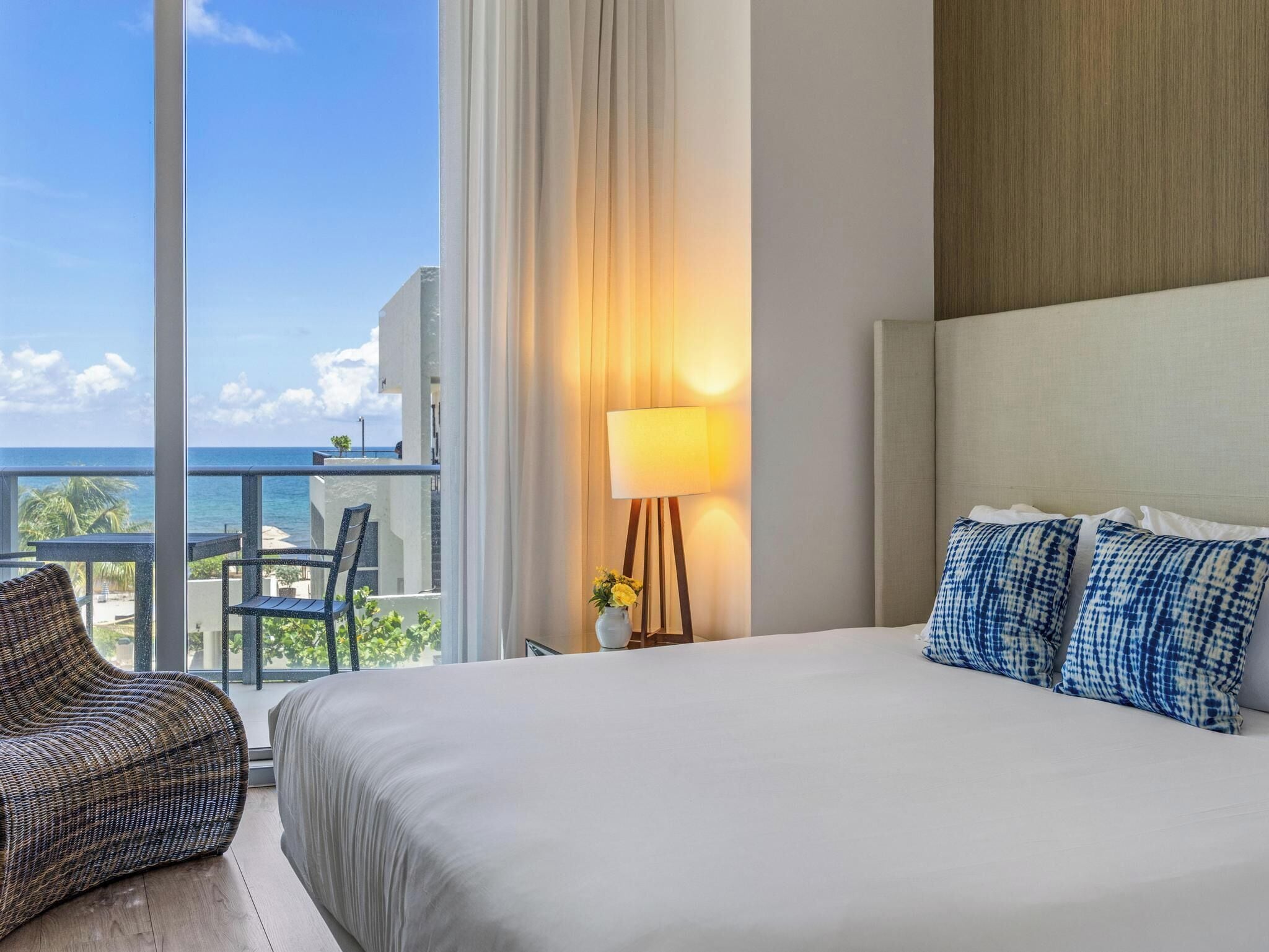 Quarto de hotel com uma cama grande, uma cadeira, uma mesa e vista para o oceano.