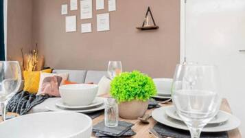 Uma mesa de jantar posta com pratos, copos e um vaso de planta.