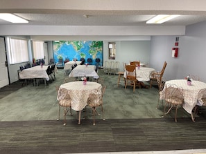 Uma sala de conferências com várias mesas e cadeiras, um mapa-múndi na parede e um extintor de incêndio.