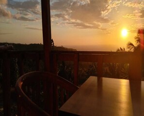Uma mesa e cadeira de madeira com vista para o pôr do sol sobre a paisagem.
