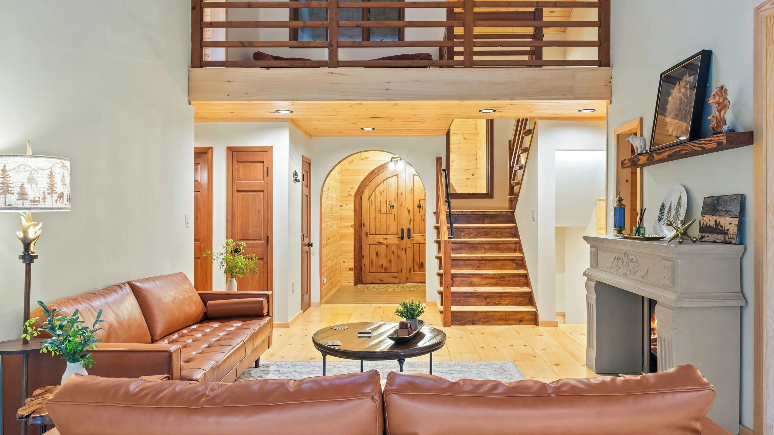 Uma sala de estar ampla com teto alto, escada de madeira e lareira.