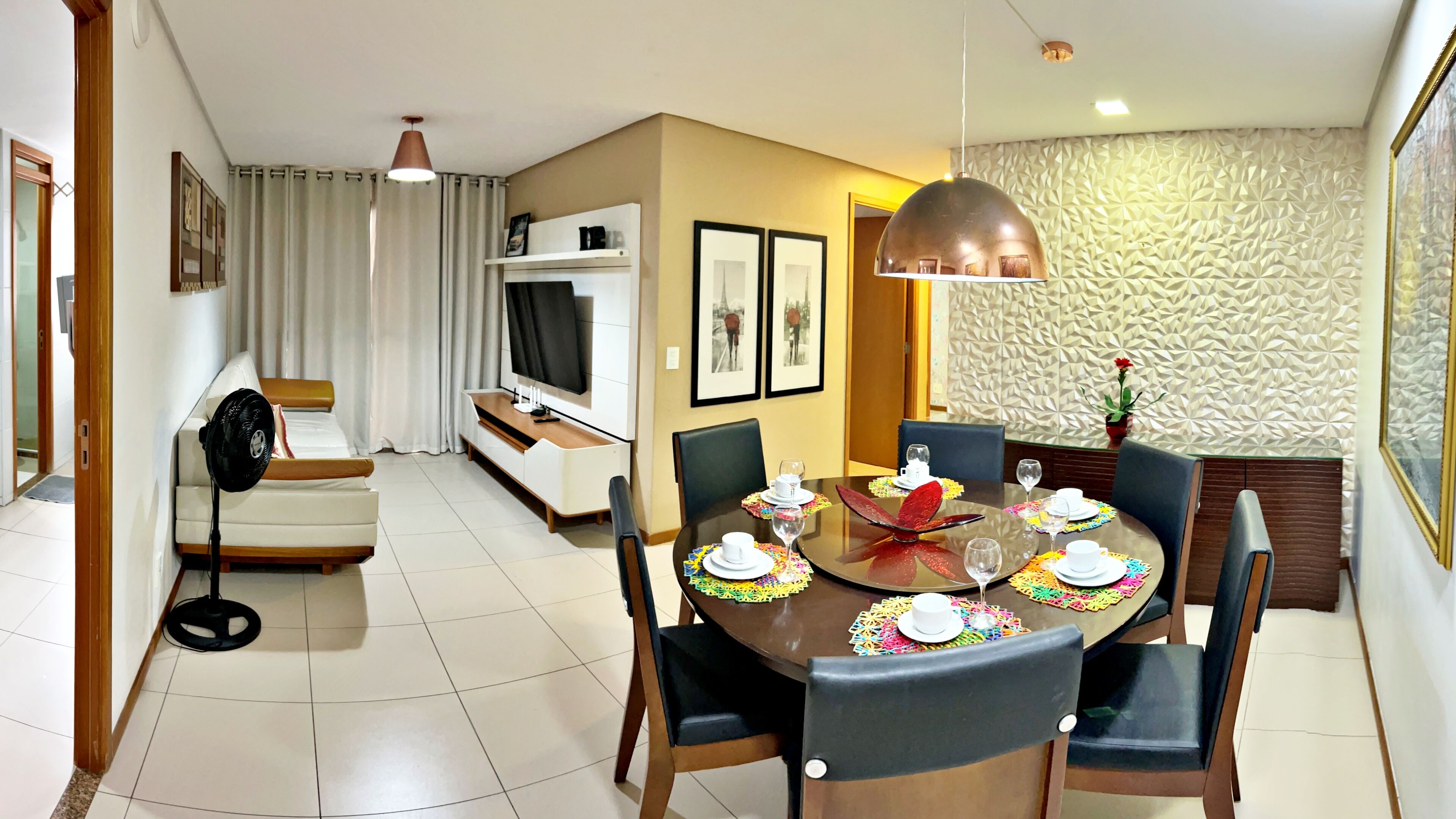 Uma sala de jantar moderna com uma mesa redonda posta para quatro pessoas, cercada por cadeiras.