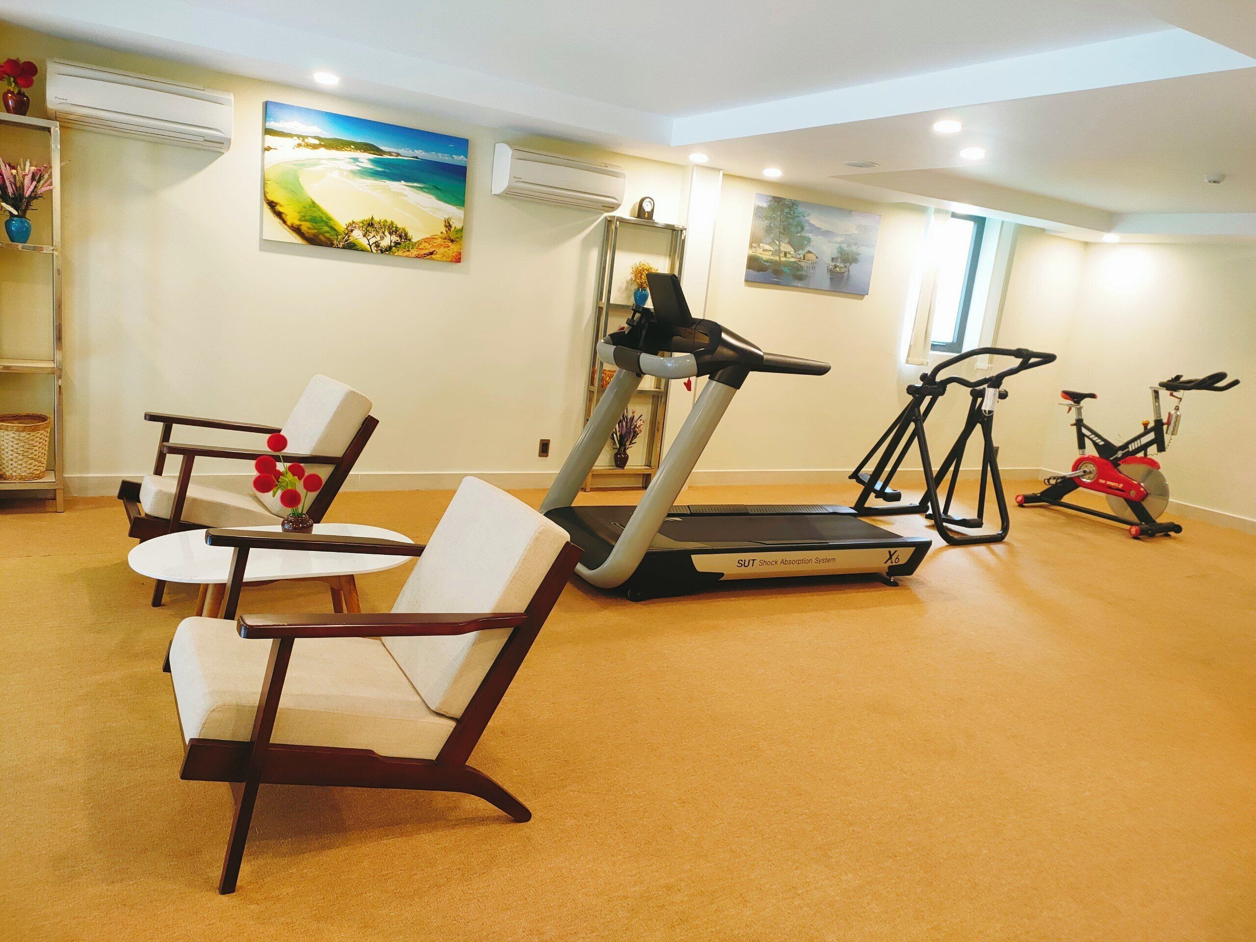 Ginásio em casa com equipamentos de exercício, incluindo esteira, bicicleta ergométrica e cadeira.