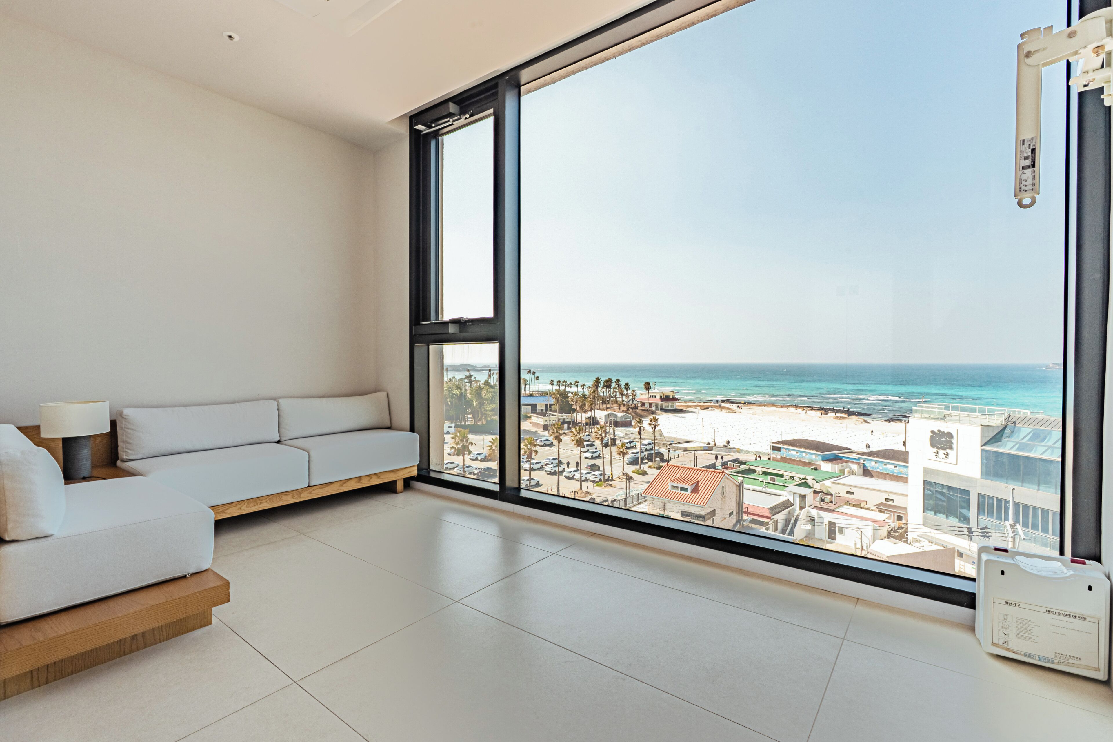 Uma sala de estar moderna com uma janela ampla que dá para a praia e o horizonte da cidade.