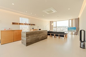 Quarto de hotel moderno com cozinha, área de estar e uma vista, além de uma janela ampla.